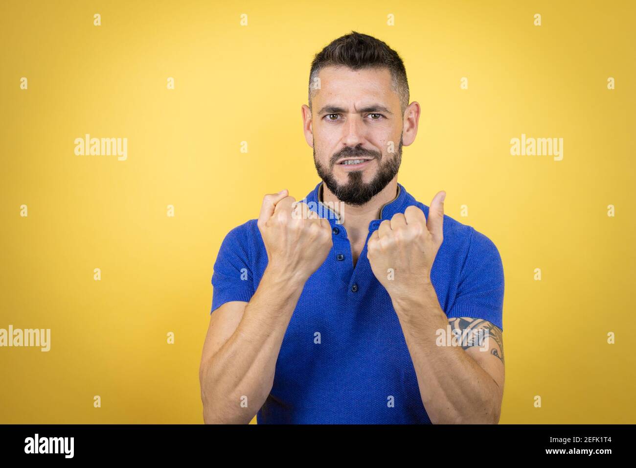 Handsome man with beard wearing blue polo shirt over yellow background ...