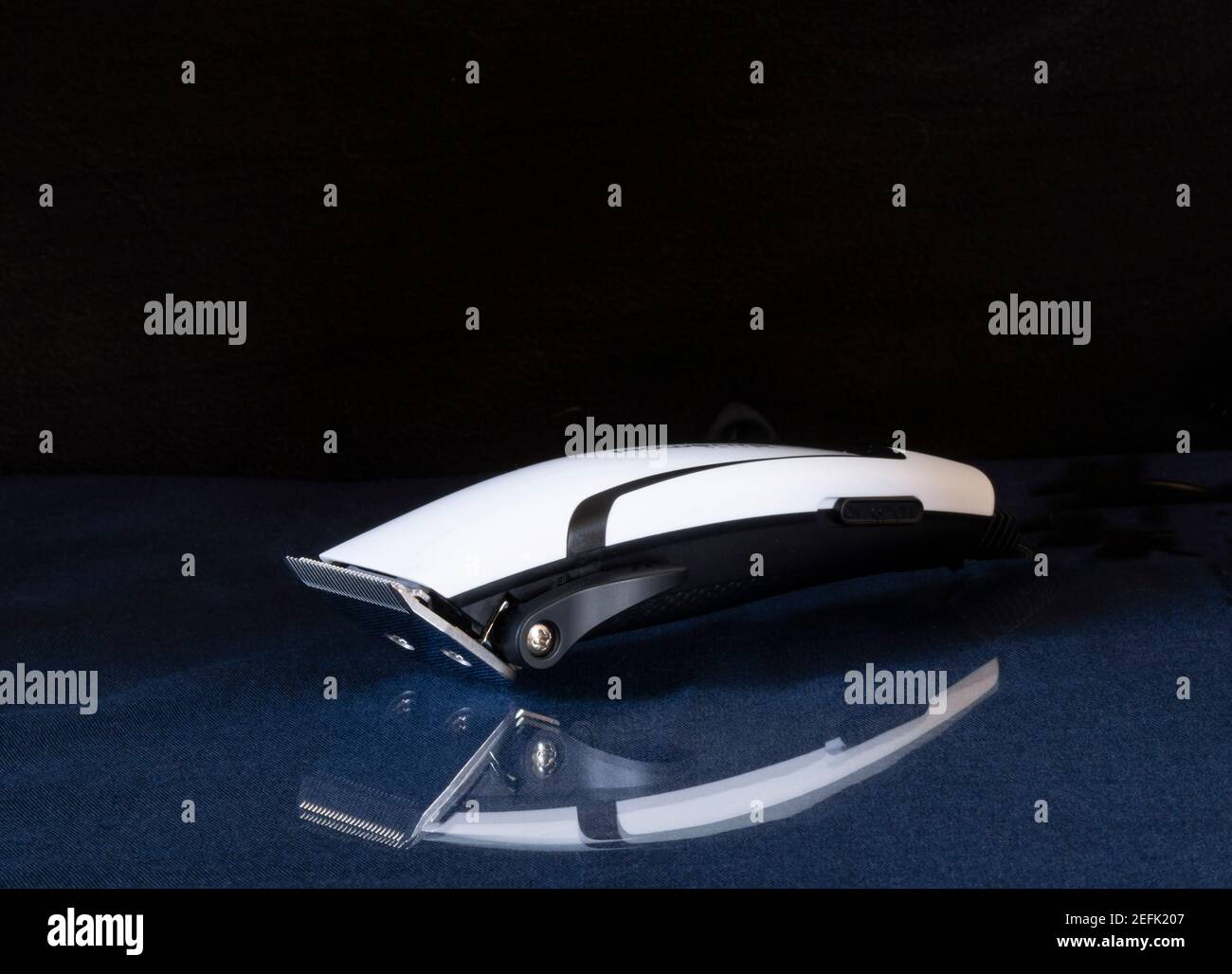 An electric razor for cutting hair is lying on a glass table. Equipment ...