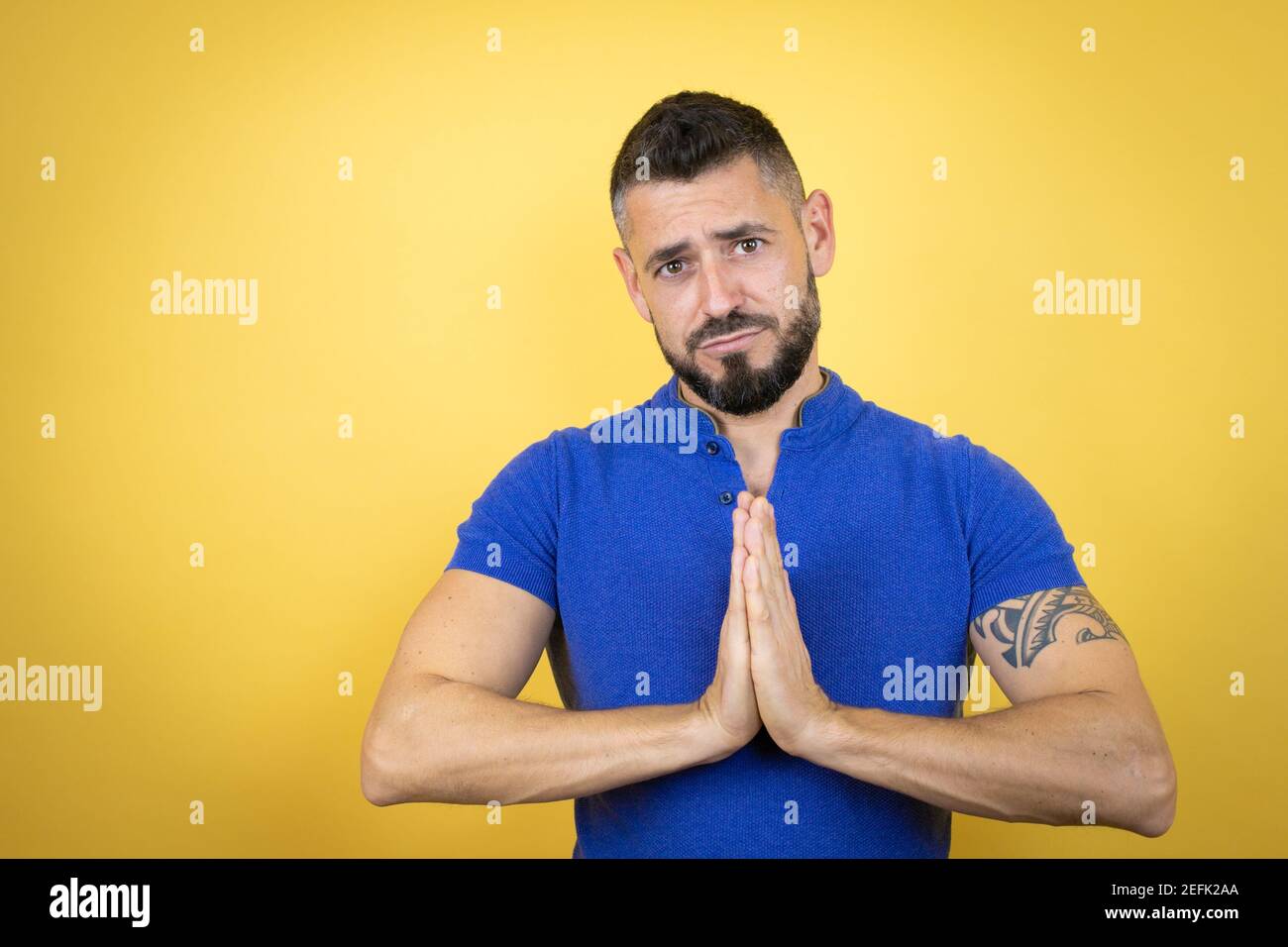 Handsome man with beard wearing blue polo shirt over yellow background ...