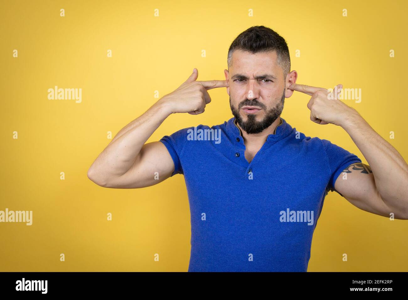 Handsome man with beard wearing blue polo shirt over yellow background ...