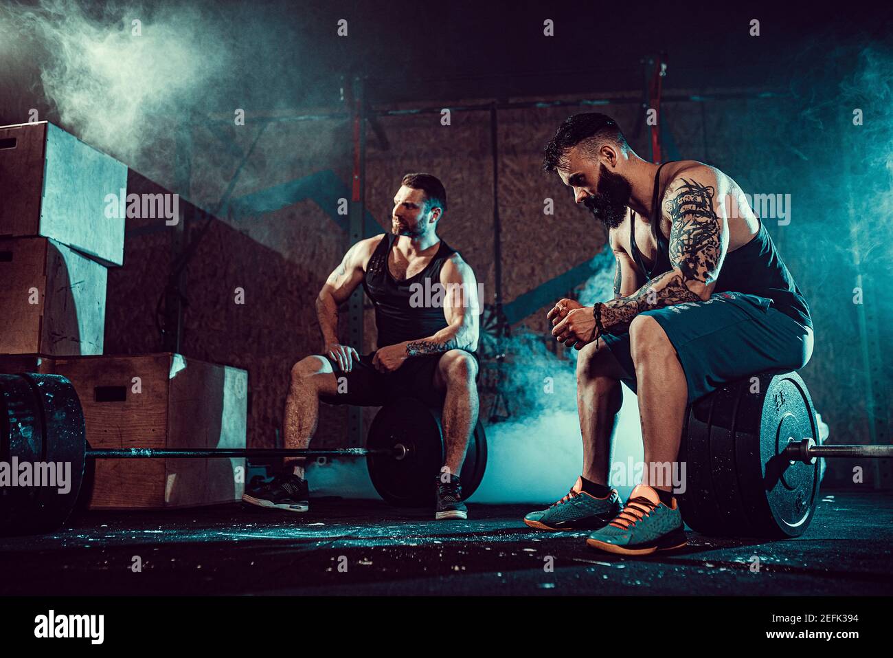 Two muscular bearded tattoed athletes relax after training, lifting ...