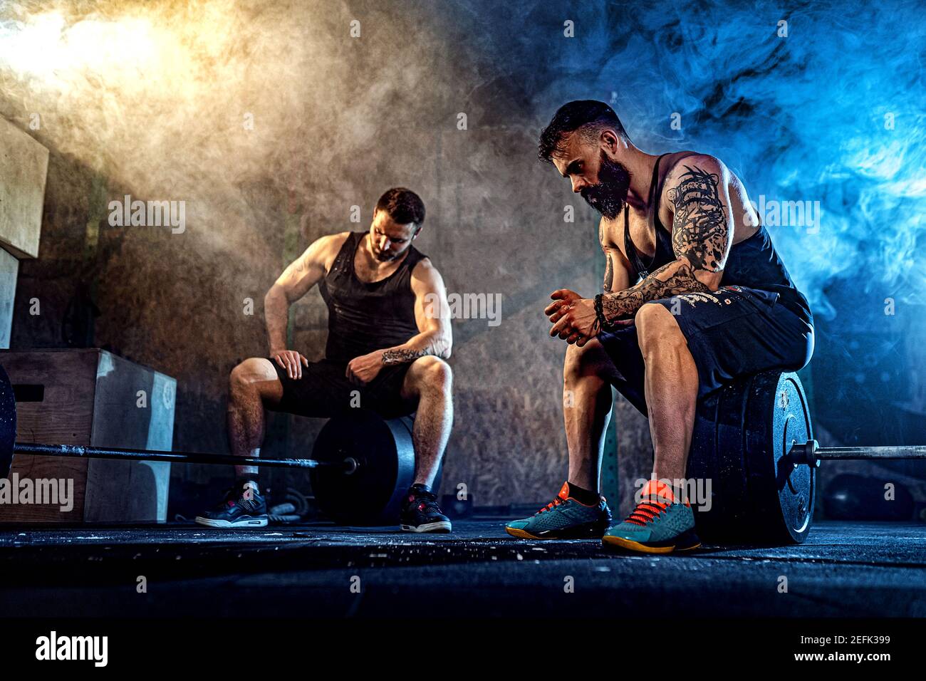 Two muscular bearded tattoed athletes relax after training, lifting ...