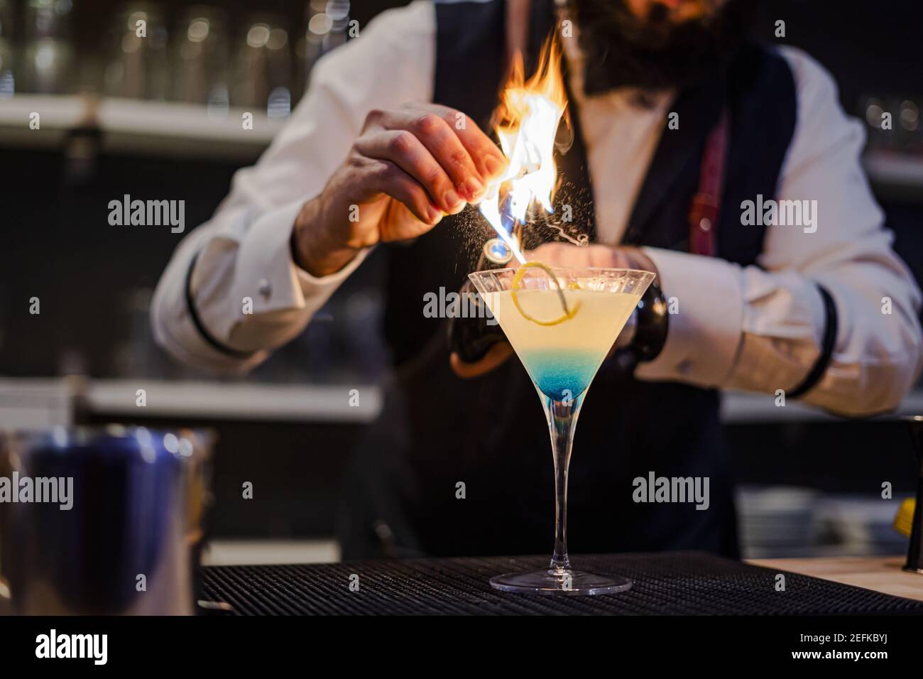 Bartender making flame over a cocktail with orange peel Stock Photo - Alamy