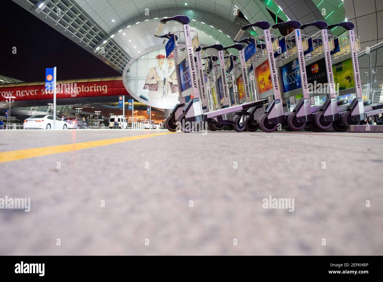 Luggage trolleys and an Emirates billboard at the drop-off zone of ...