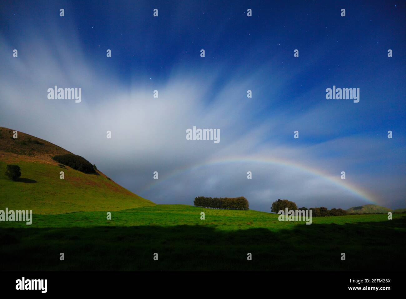 Moonbow appears over high pasture in the full moon night in Big Island ...