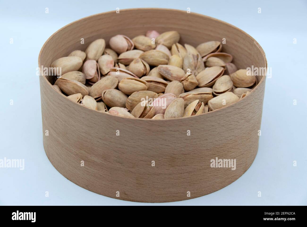 Salted pistachios in a wooden round box on a white background Stock ...