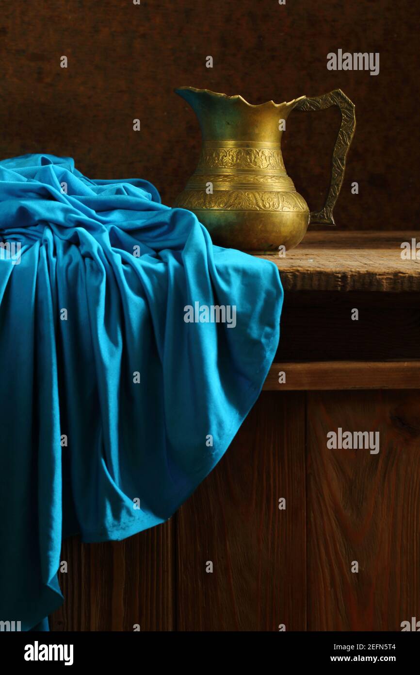 Still life with a copper jug with a blue tablecloth Stock Photo - Alamy
