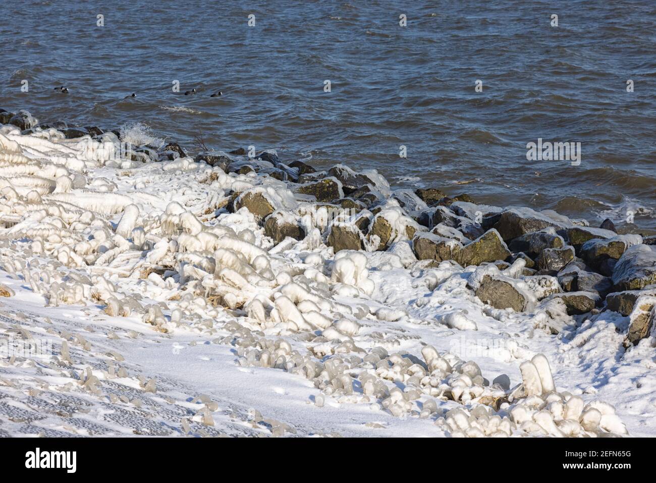 Dutch breakwater with basalt stones covered with ice in wintertime ...