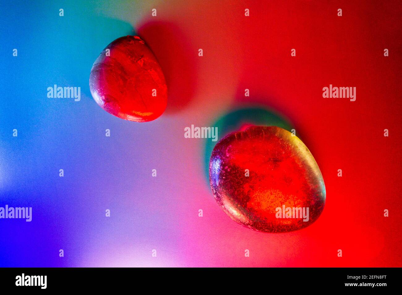 Two tumbled mineral gems colorfully illuminated showing abstract ...