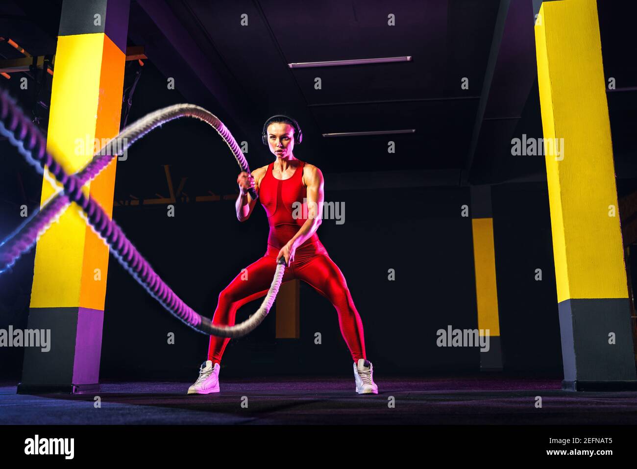 Fitness woman using training ropes for exercise at gym. Athlete working ...