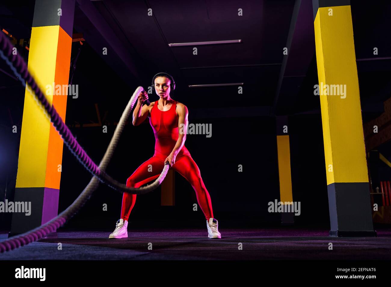 Fitness woman using training ropes for exercise at gym. Athlete working ...