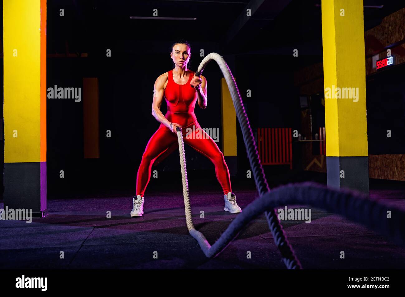 Fitness woman using training ropes for exercise at gym. Athlete working ...