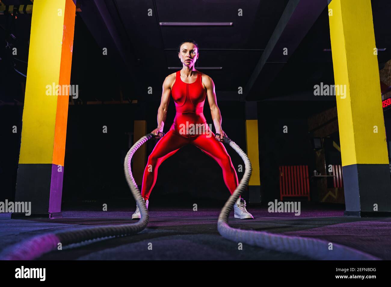 Fitness woman using training ropes for exercise at gym. Athlete working ...