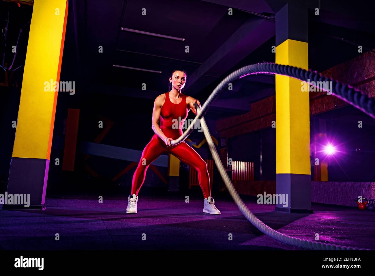 Fitness woman using training ropes for exercise at gym. Athlete working ...