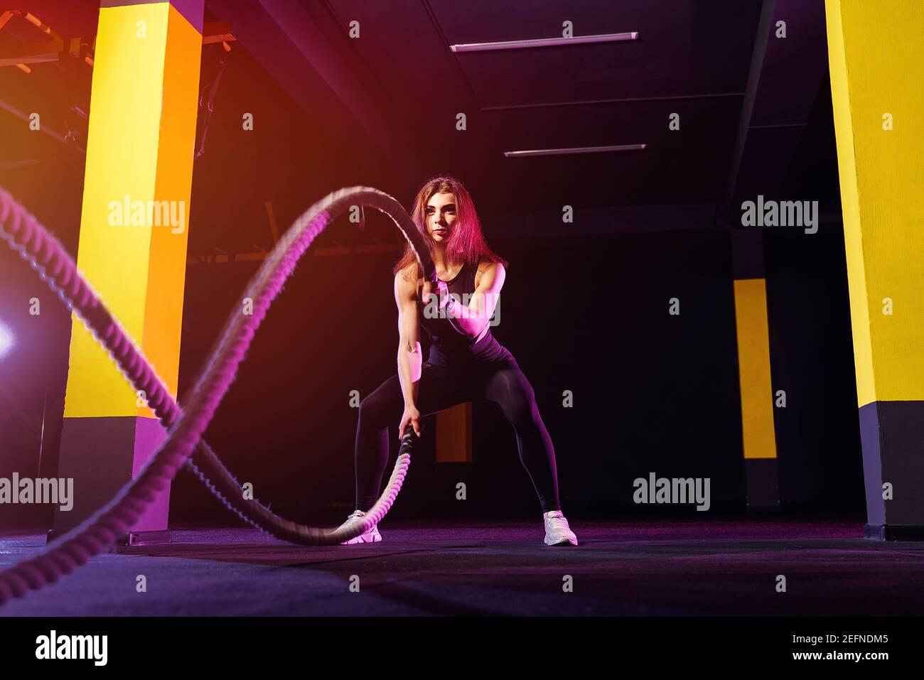 Fitness woman using training ropes for exercise at gym. Athlete working ...