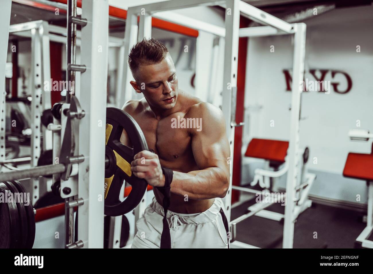 Bodybuilder preparing for heavyweight exercise with barbell in gym ...