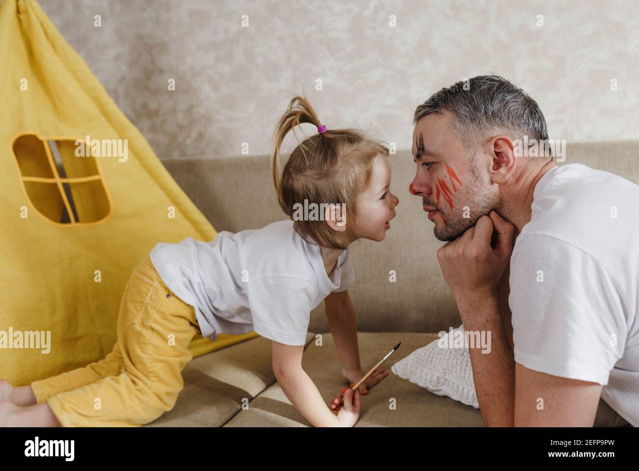 dad and little daughter play together at home on the couch, carefully examining each other Stock ...