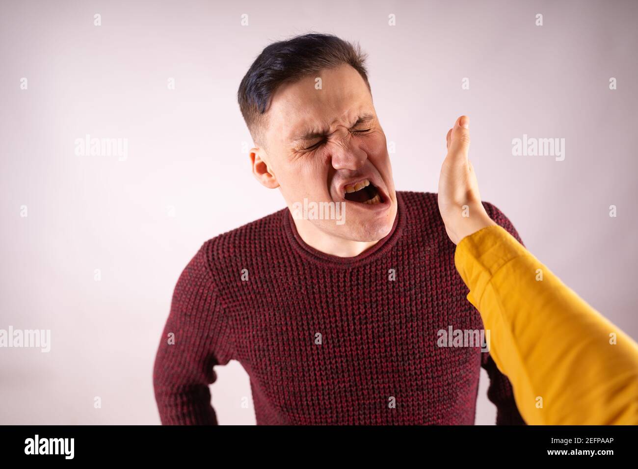 Crop person slapping scared man in face. Emotional male getting slapped ...