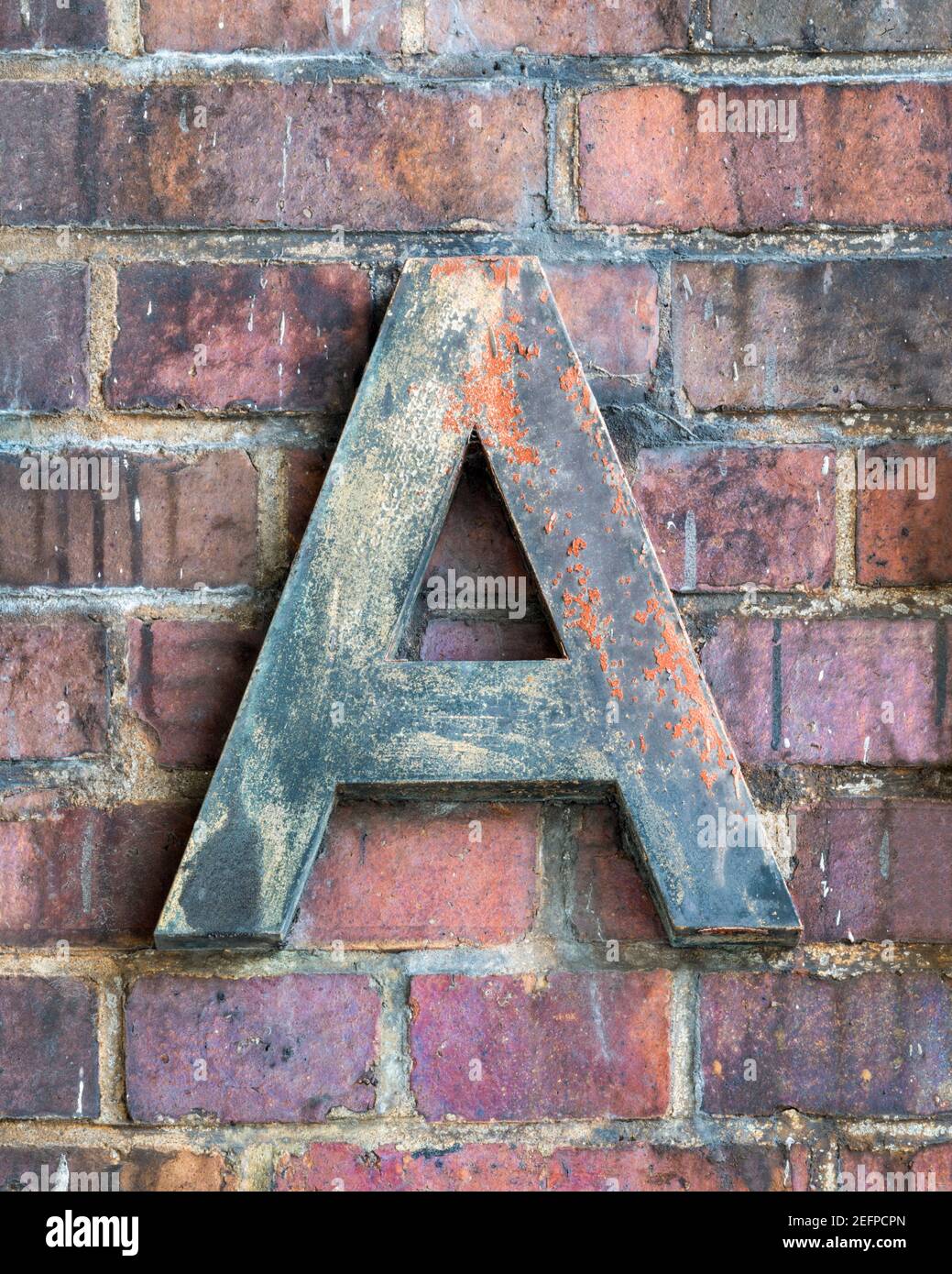 Green metal letter A in front of a brick wall Stock Photo - Alamy