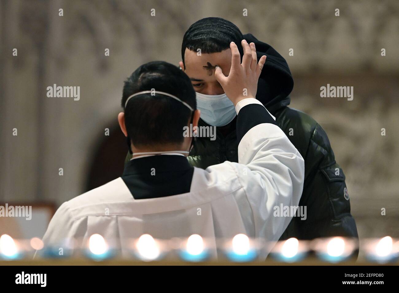 A seminarian places ash on the forehead of a church goer inside St ...