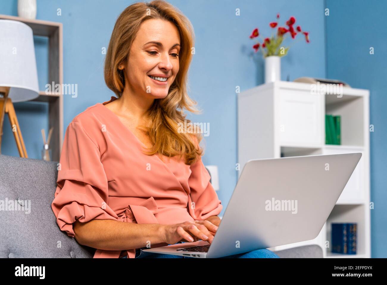 Beautiful adult woman sitting alone at home and working on computer ...