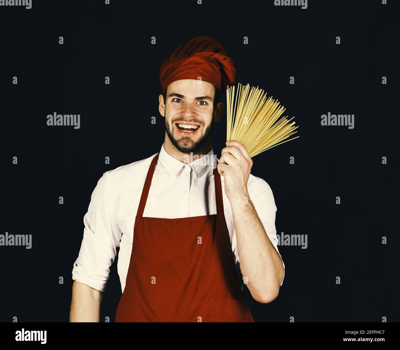 Chef with smiling face holds bunch of spaghetti on black background ...