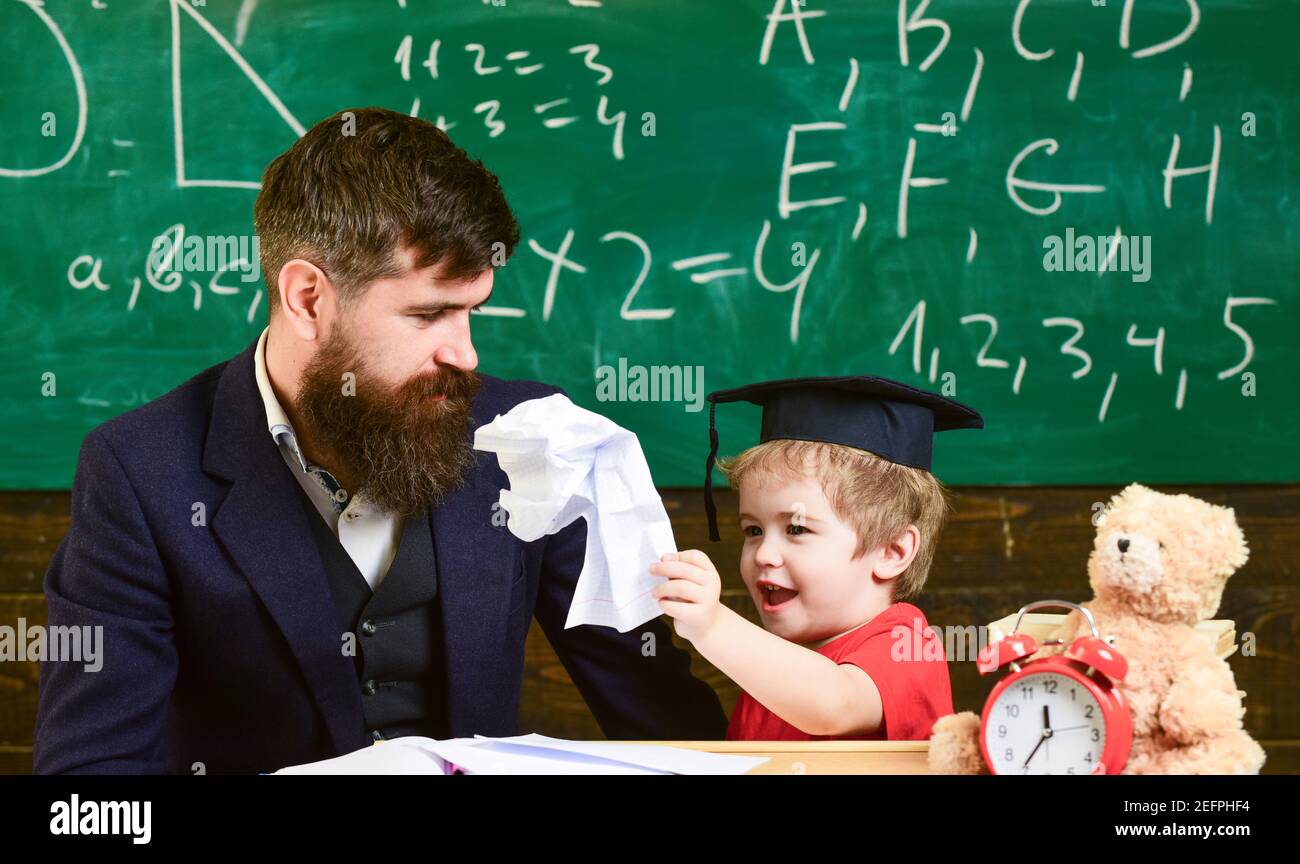 Teacher with beard, father teaches little son in classroom, chalkboard ...