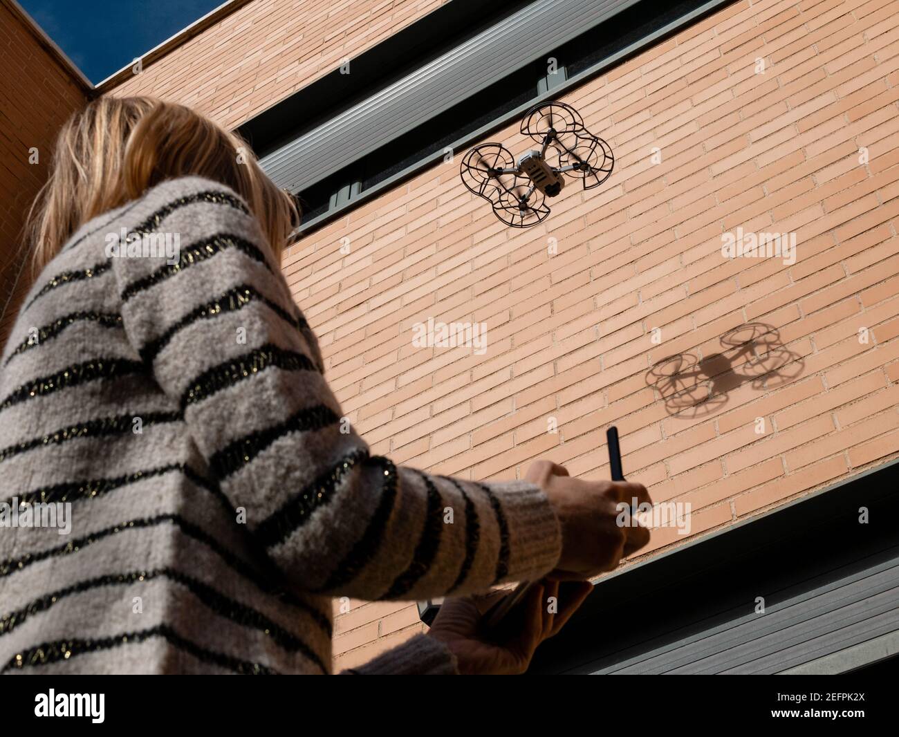 Low angle shot of a Caucasian woman piloting a drone at a backyard ...