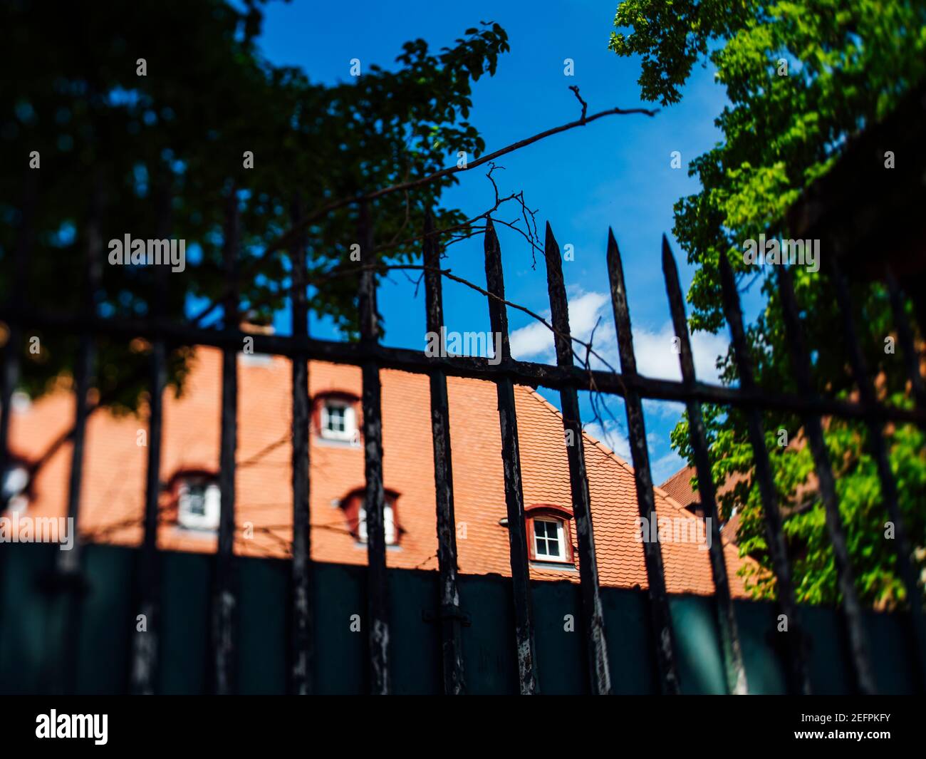 View through tall sharp security fence of rooftop of a luxury mansion ...