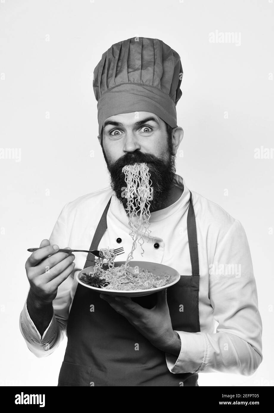 Young chef man eating japanese or italian noodles in restaurant on grey ...