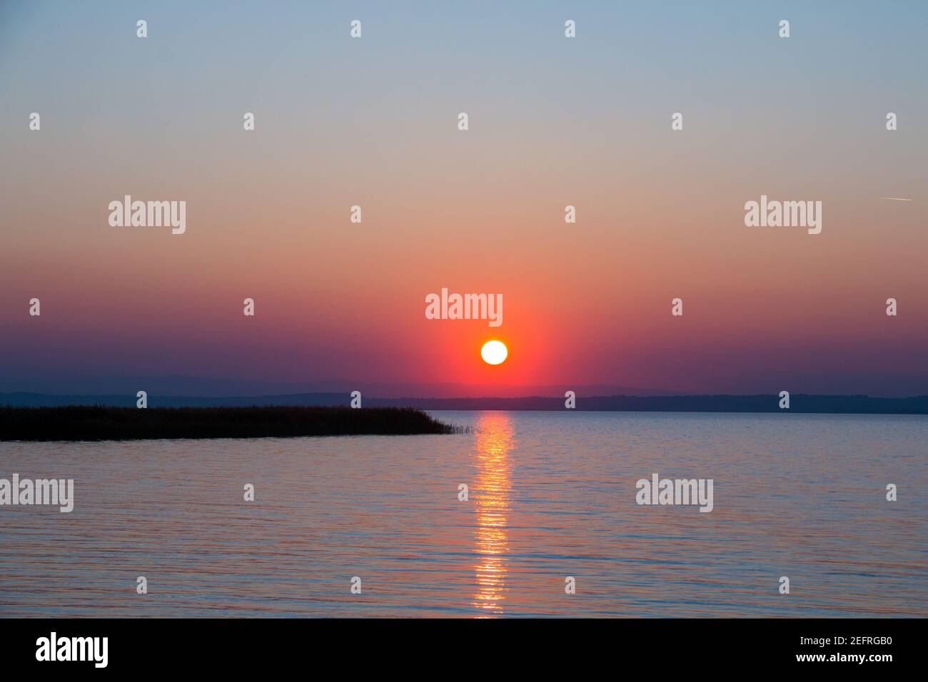 Golden setting sun over the sea just above horizon with optic straight ...