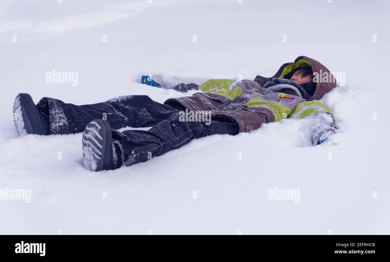 A young boy (8 yr old) lying on his back in deep snow Stock Photo - Alamy