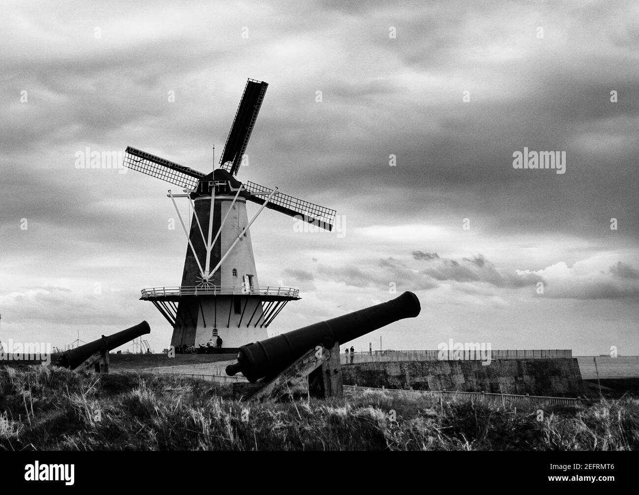 Grayscale shot of a windmill with cannons on the ground Stock Photo - Alamy