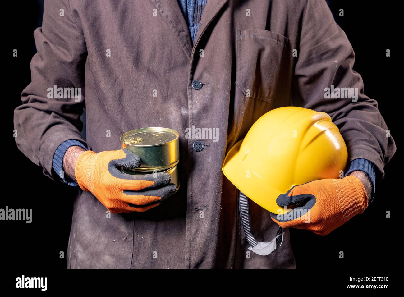 A production worker with a canned meat with a helmet on his hands. A ...
