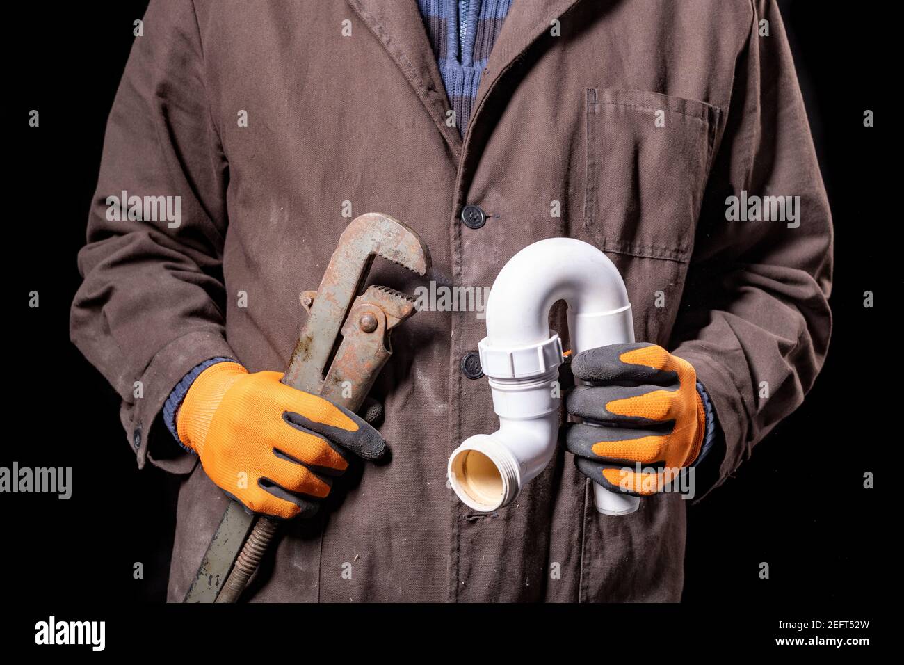 Plumber holding an adjustable wrench and a siphon to the wash basin ...