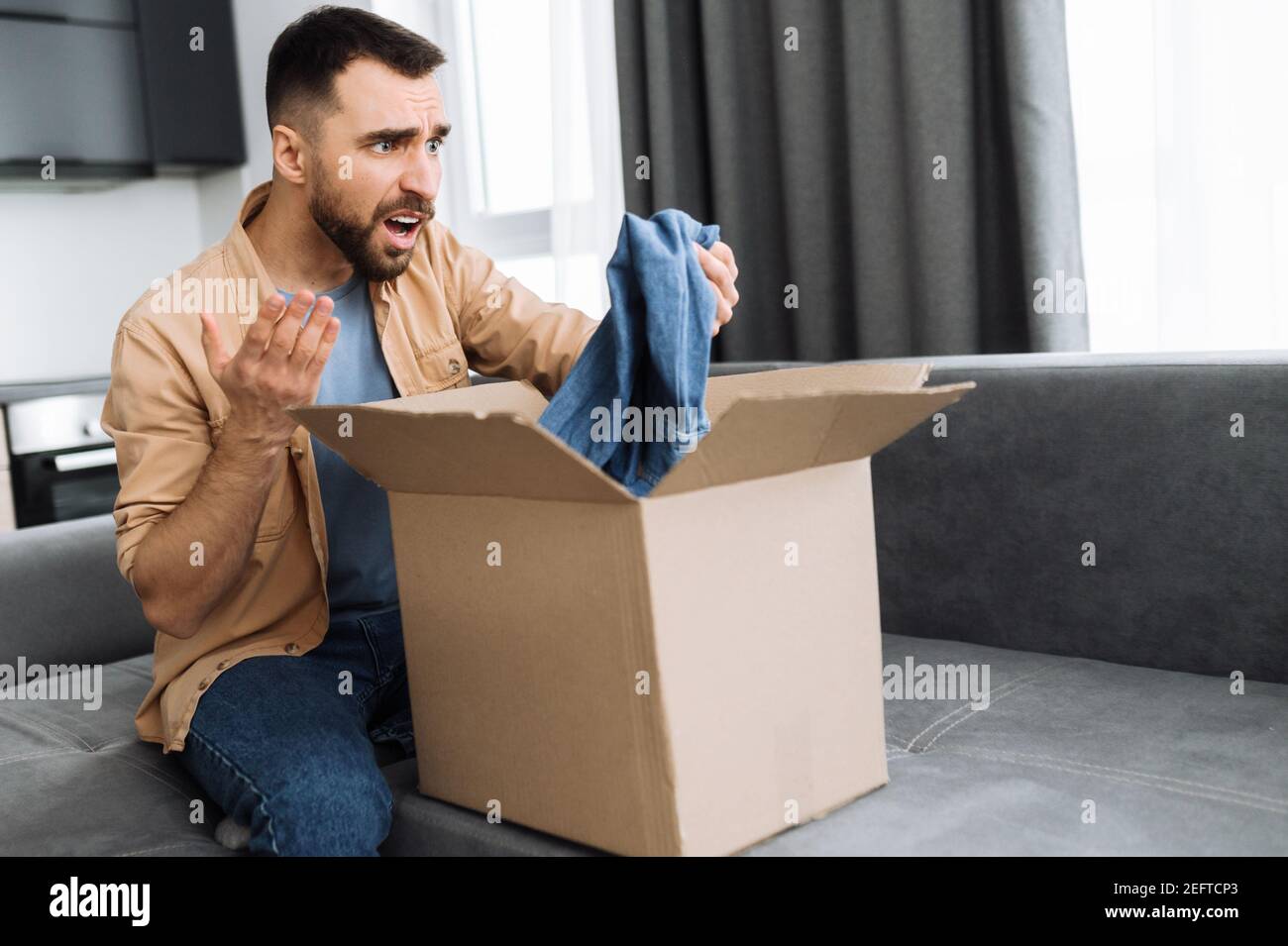 Confused caucasian male unpacking his parcel. Surprised man got an ...