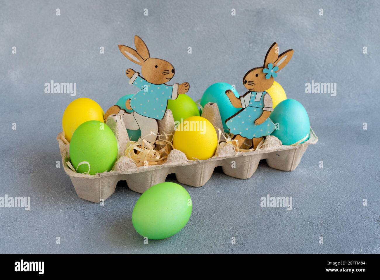 Multicolor easter eggs with easter bunnies in egg carton on grey ...