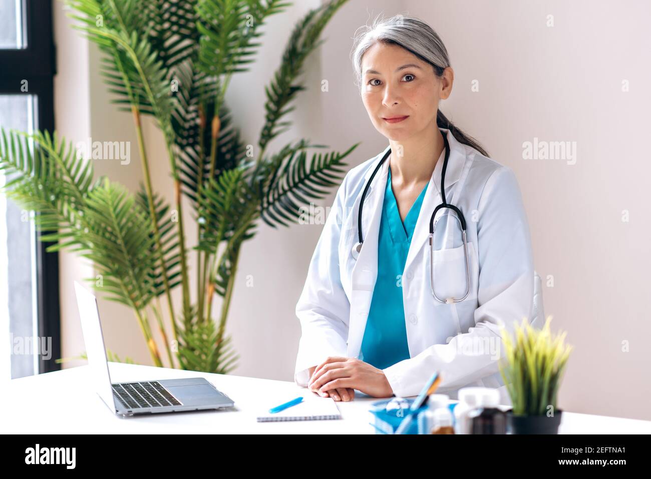 Gray-haired female middle aged general doctor dressed in medical ...