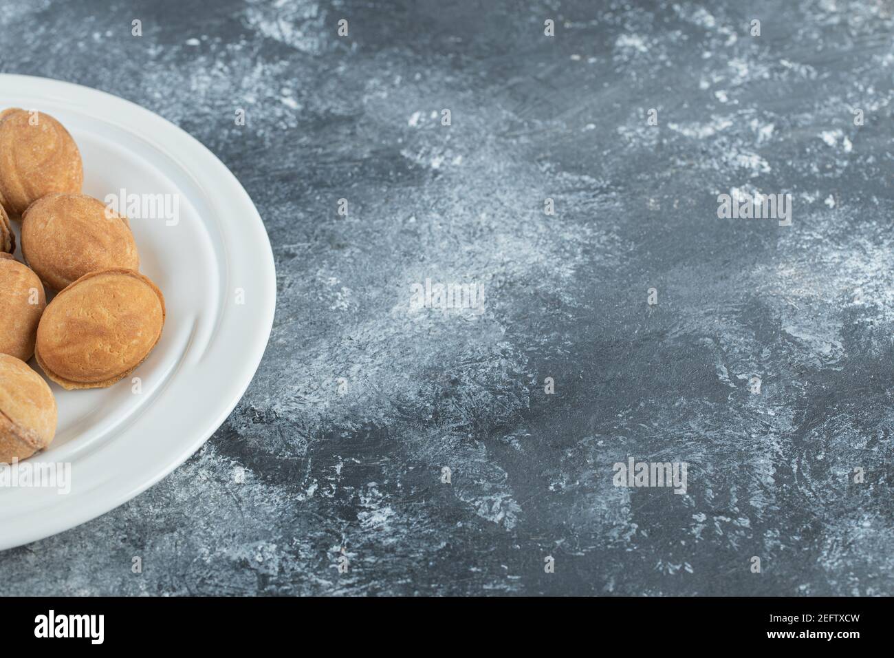 A white plate full of sweet walnut shaped cookies Stock Photo - Alamy