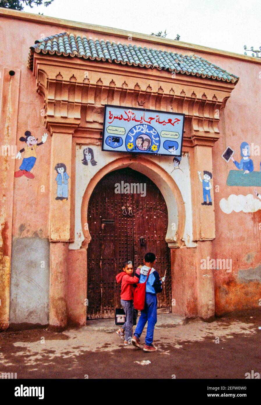 Two boys walking past a school wooden gate in Marrakesh, Morocco Stock ...