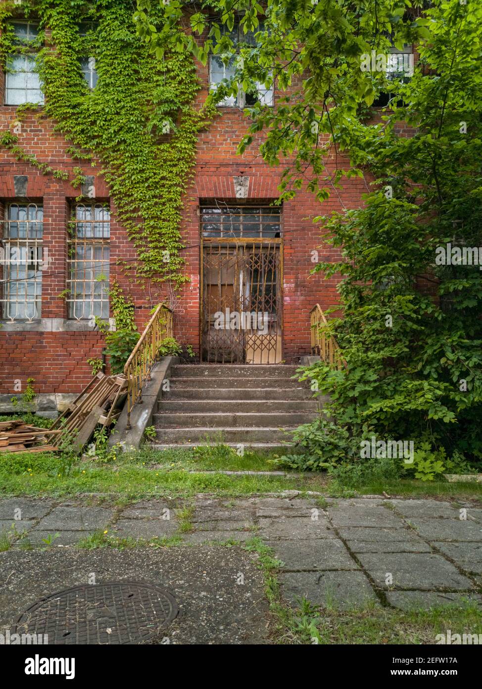 Facade of old brick building with concrete stairs, barred doors and ...