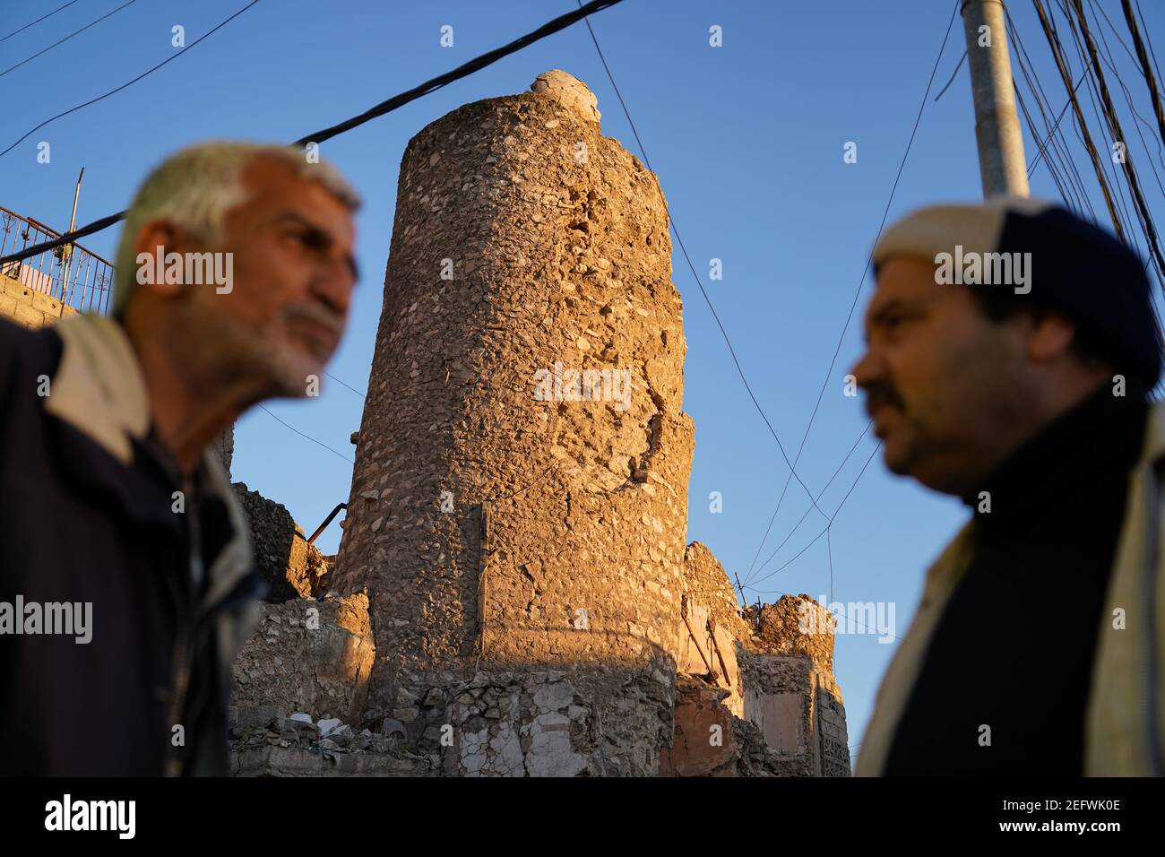 Two men having a chat with the minaret of the damaged mosque in the ...