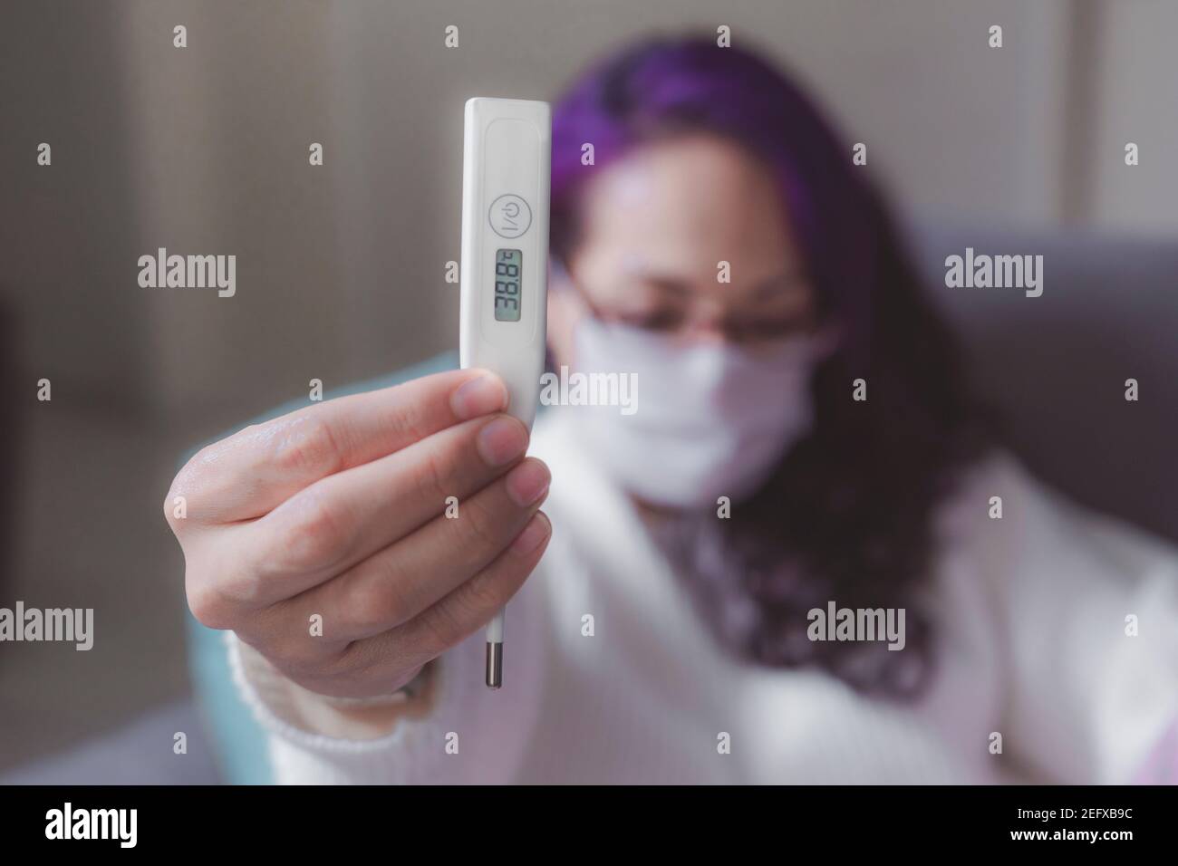 View of a thermometer shown by a woman in the background, she is in ...