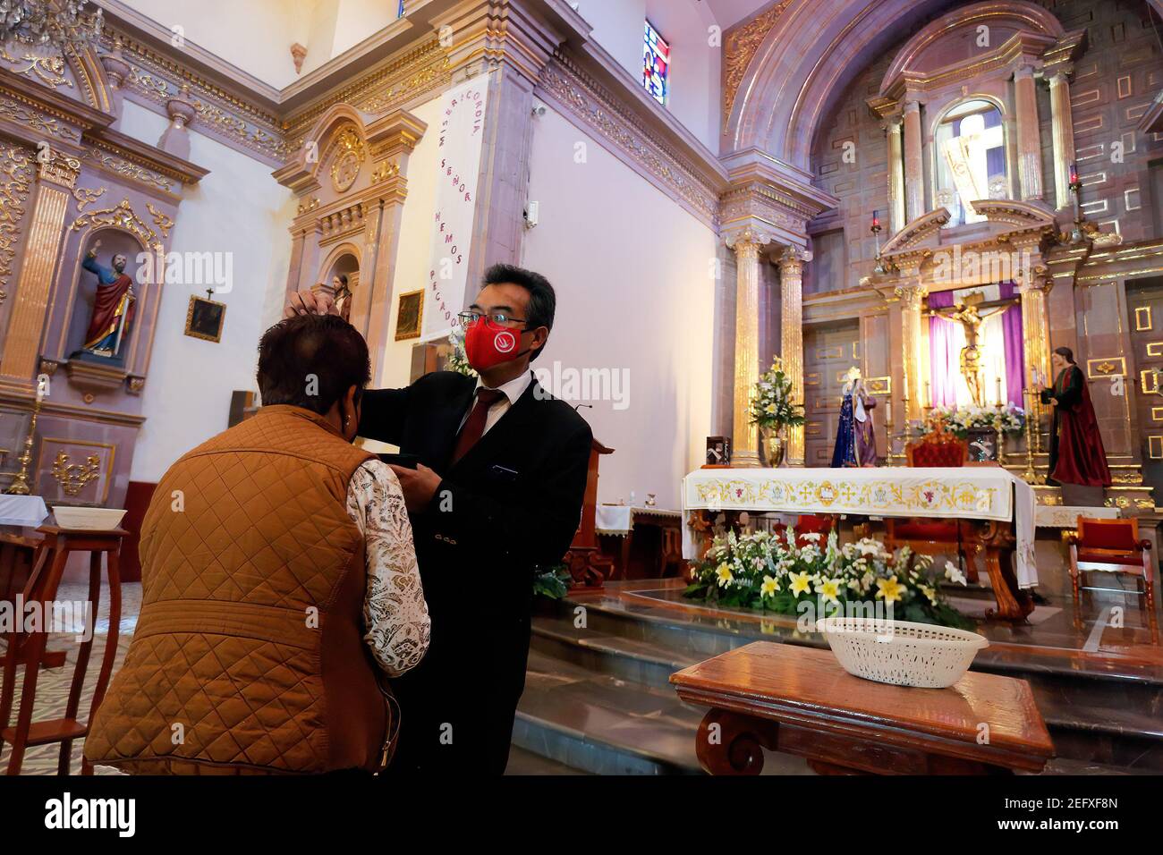 A priest applies ash on a woman's head at a catholic church. Ash ...