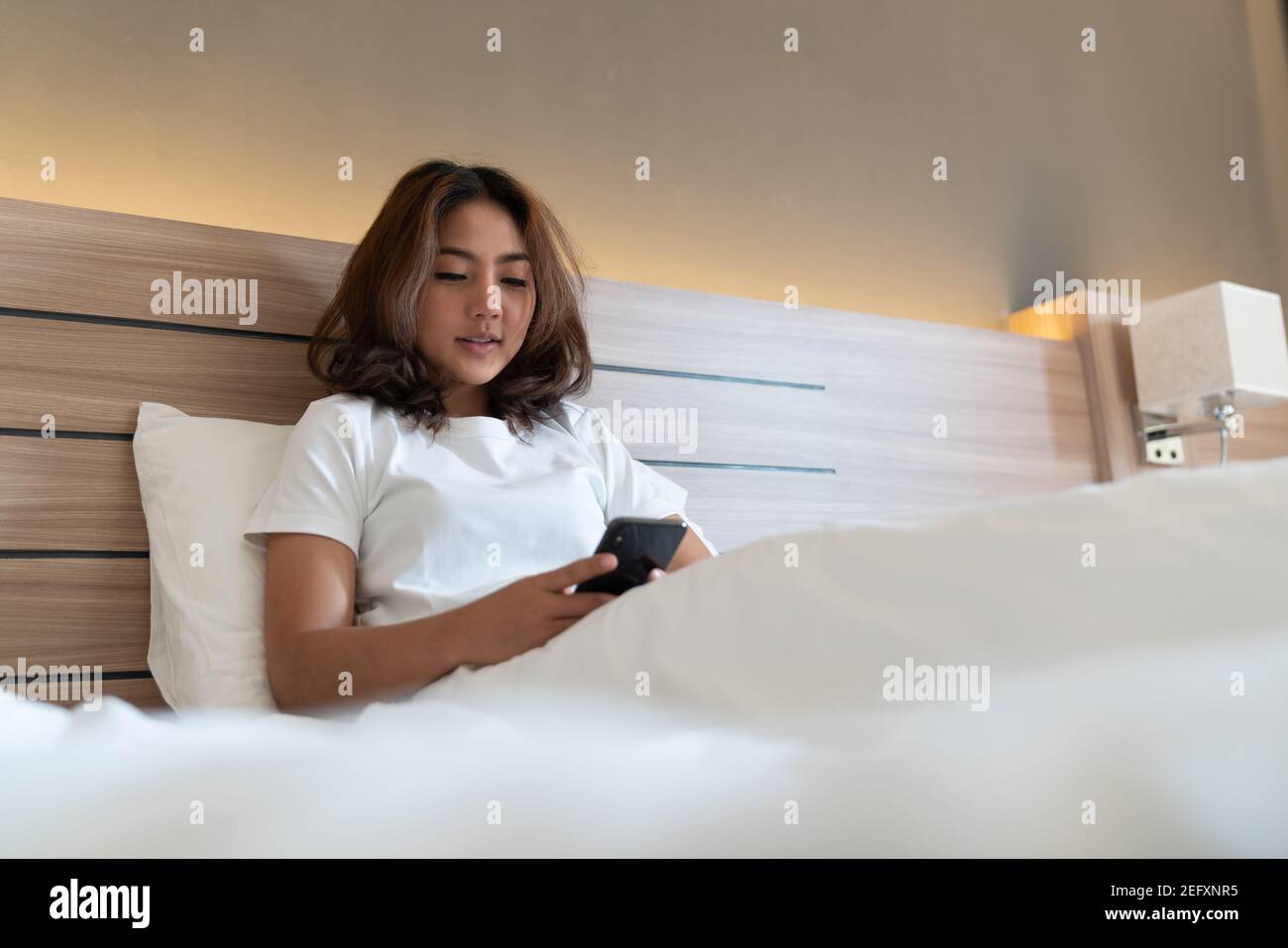 Young asian women lying in bed texting and checking social apps in ...