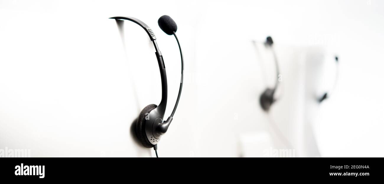 Microphone headsets hanging on computer monitors in call center ...