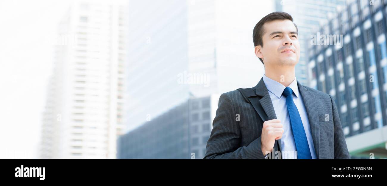 Businessman carrying bag and looking forward on blur office building ...