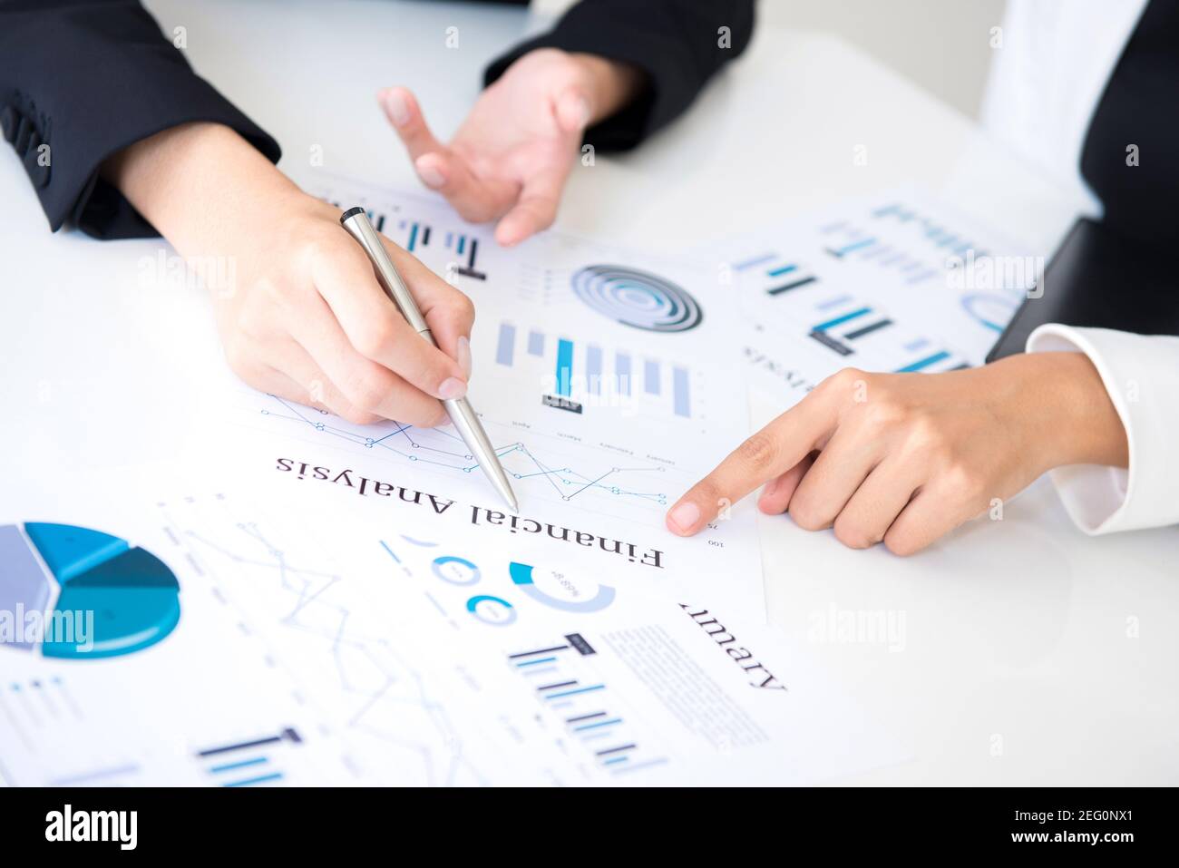 Business people discussing and analyzing documents at meeting table ...