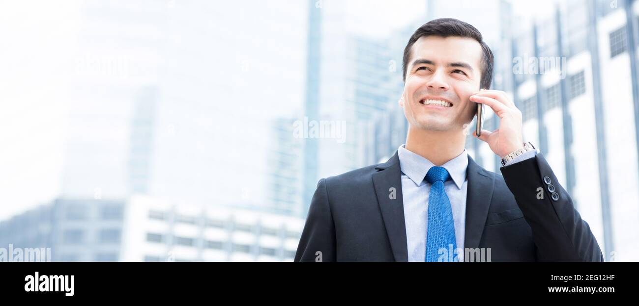 Smiling businessman calling on smartphone in bur office building ...