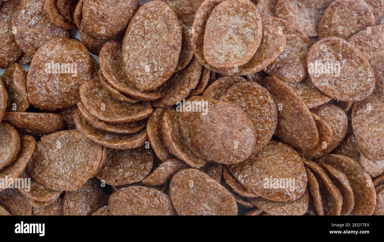 A pile of brown chocolate oval shaped flakes-muesli lying on top of ...
